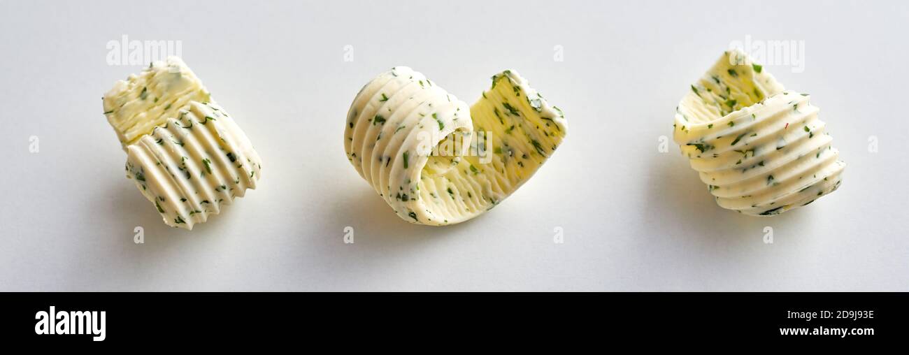 Three elegant spiral butter curls seasoned with fresh herbs on white in ...
