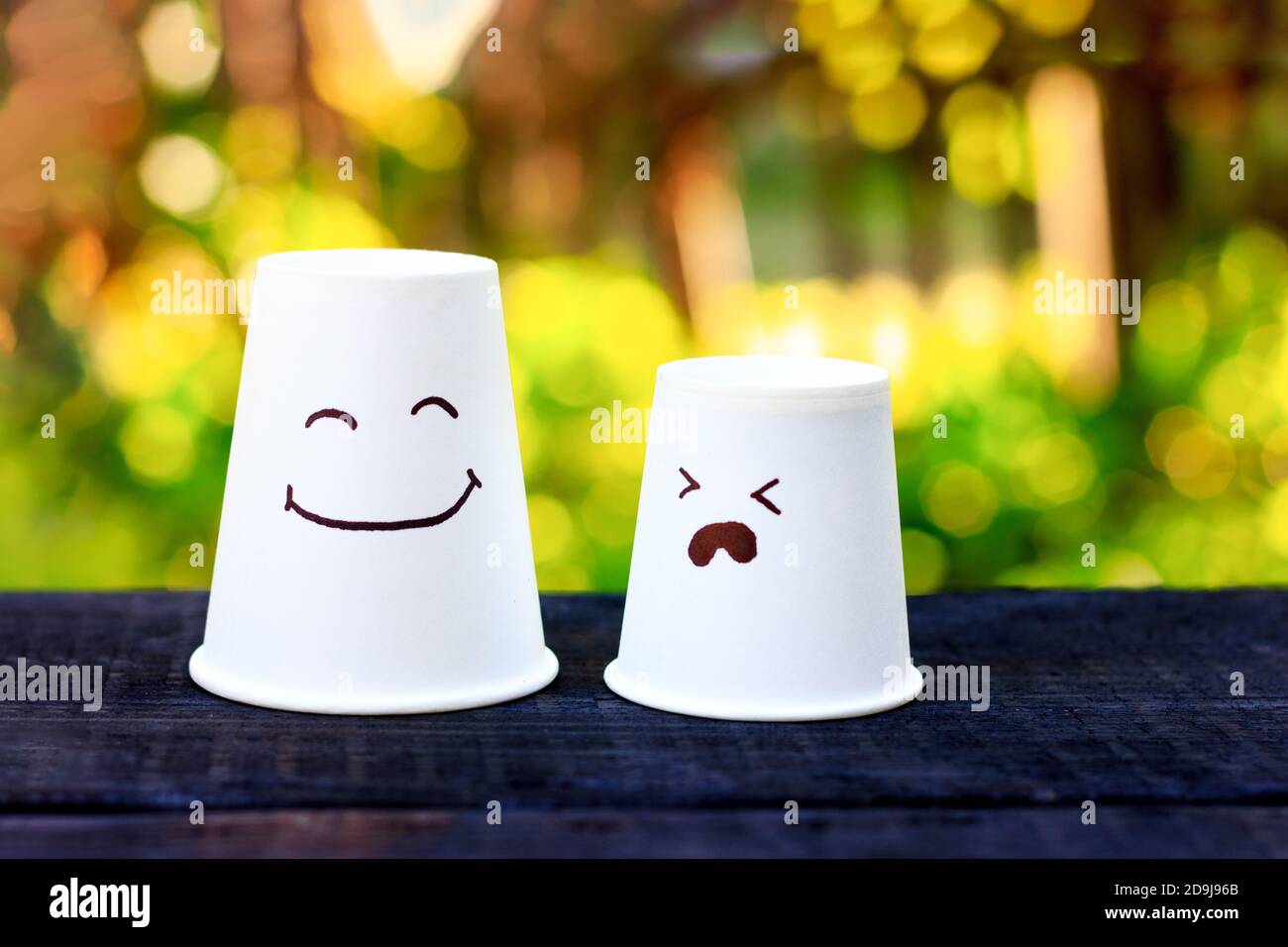 A sad and cheerful disposable cup. Symbolism of human relationships ...