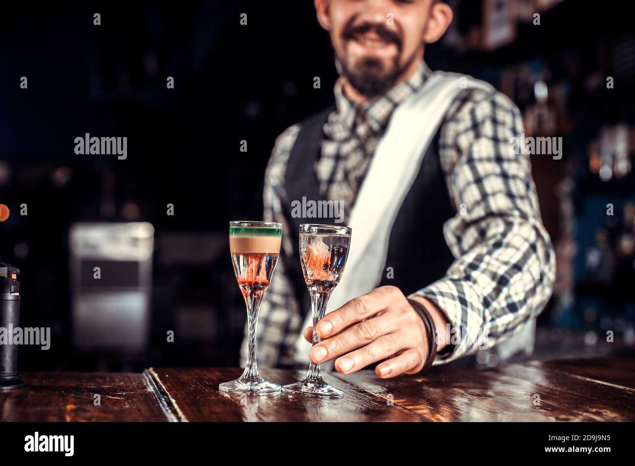 Professional barman decorates colorful concoction while standing near ...