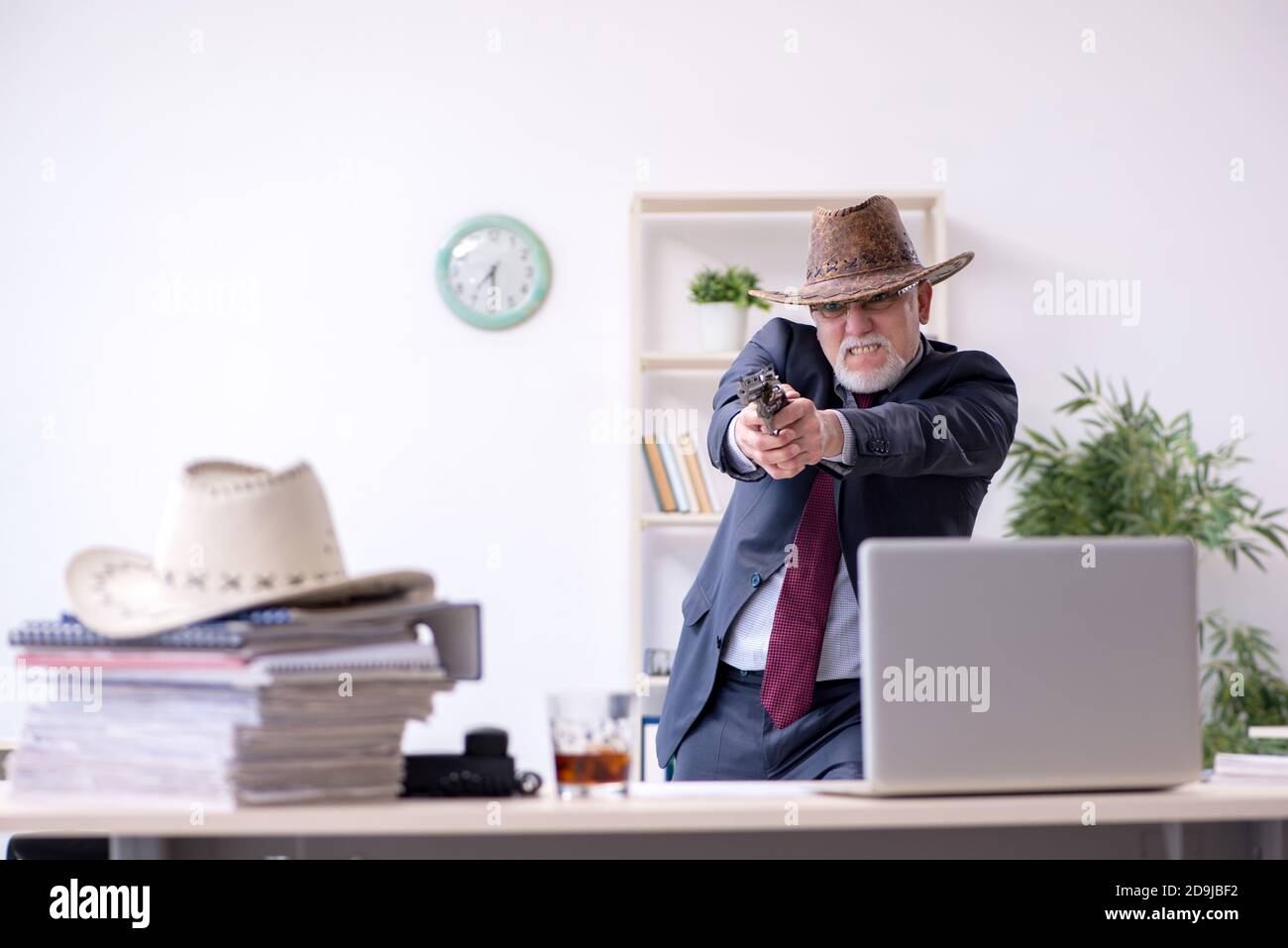 Funny old boss in cowboy hat in office Stock Photo - Alamy