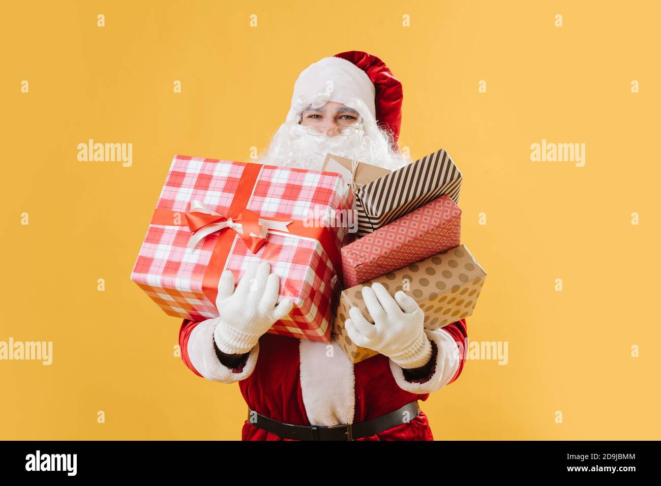 Happy satisfied Santa Claus holding stack of wrapped presents for ...