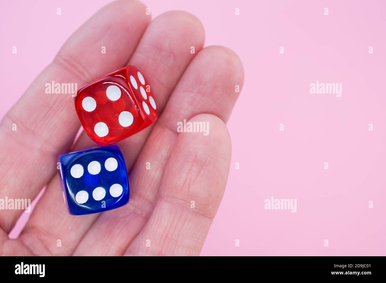 Closeup shot of a hand holding red and blue dice isolated on pink ...