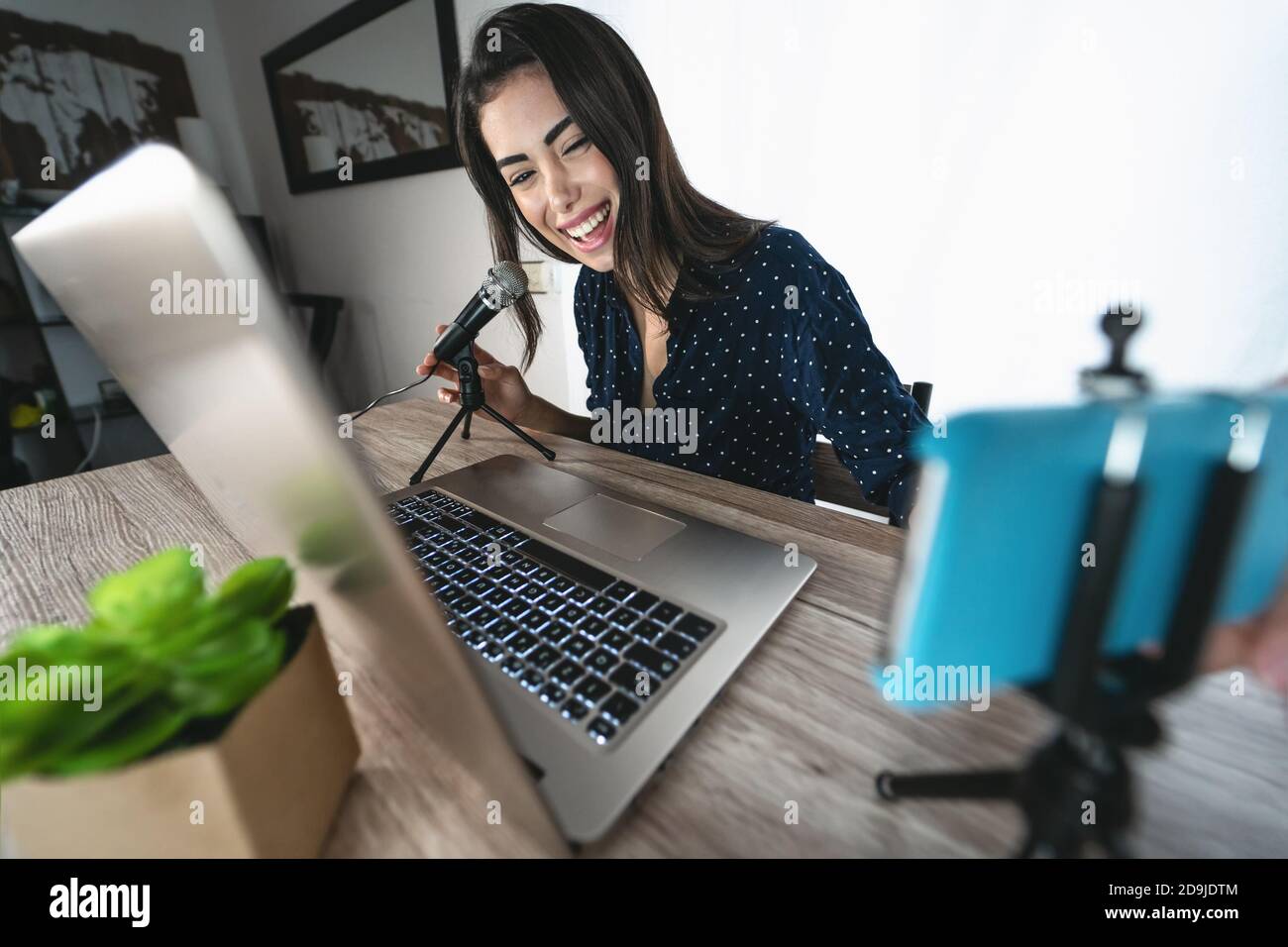 Happy woman filming video podcast with smart phone camera while using ...