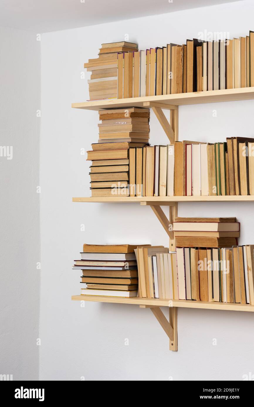 Light wooden bookshelves with hardback overturned books in white ...