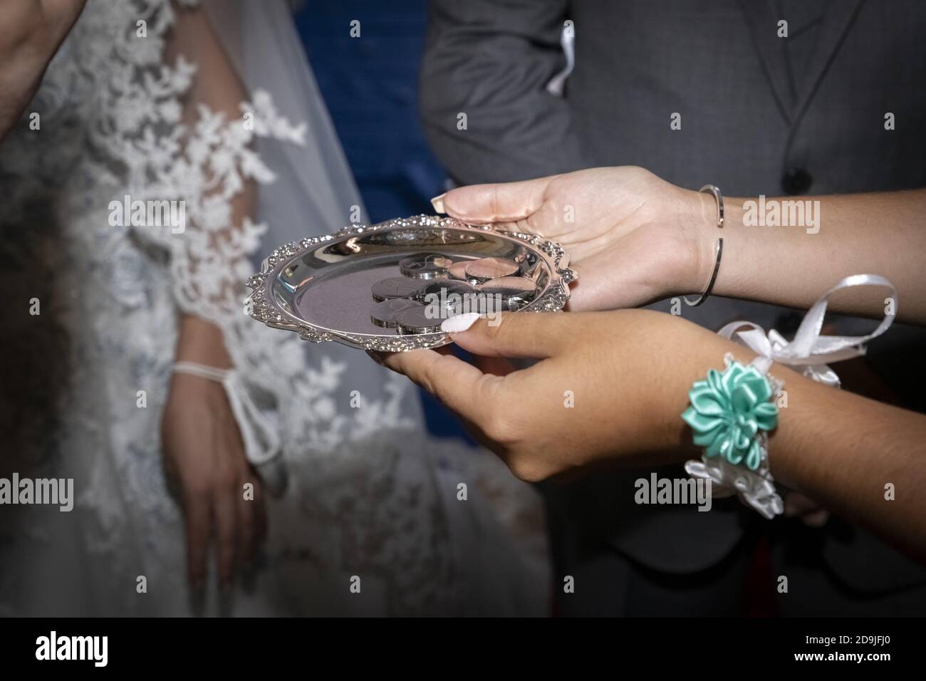 Closeup of a bridesmaid holding the traditional wedding coins on a tray ...