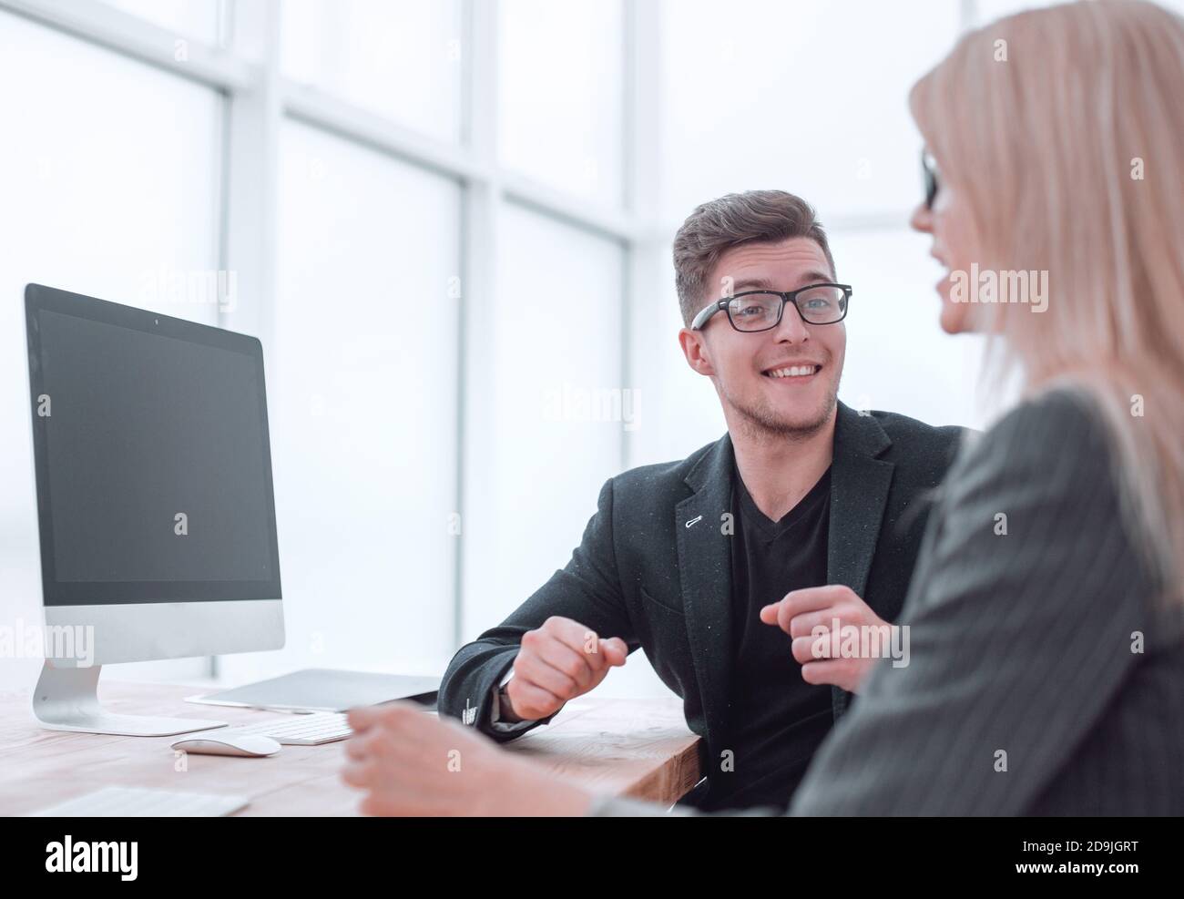 two business colleagues discussing a work project at the desktop Stock ...