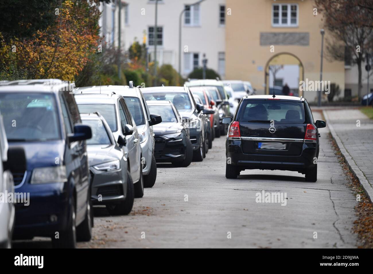Car drives into a one-way street in a residential area. Parked cars are ...