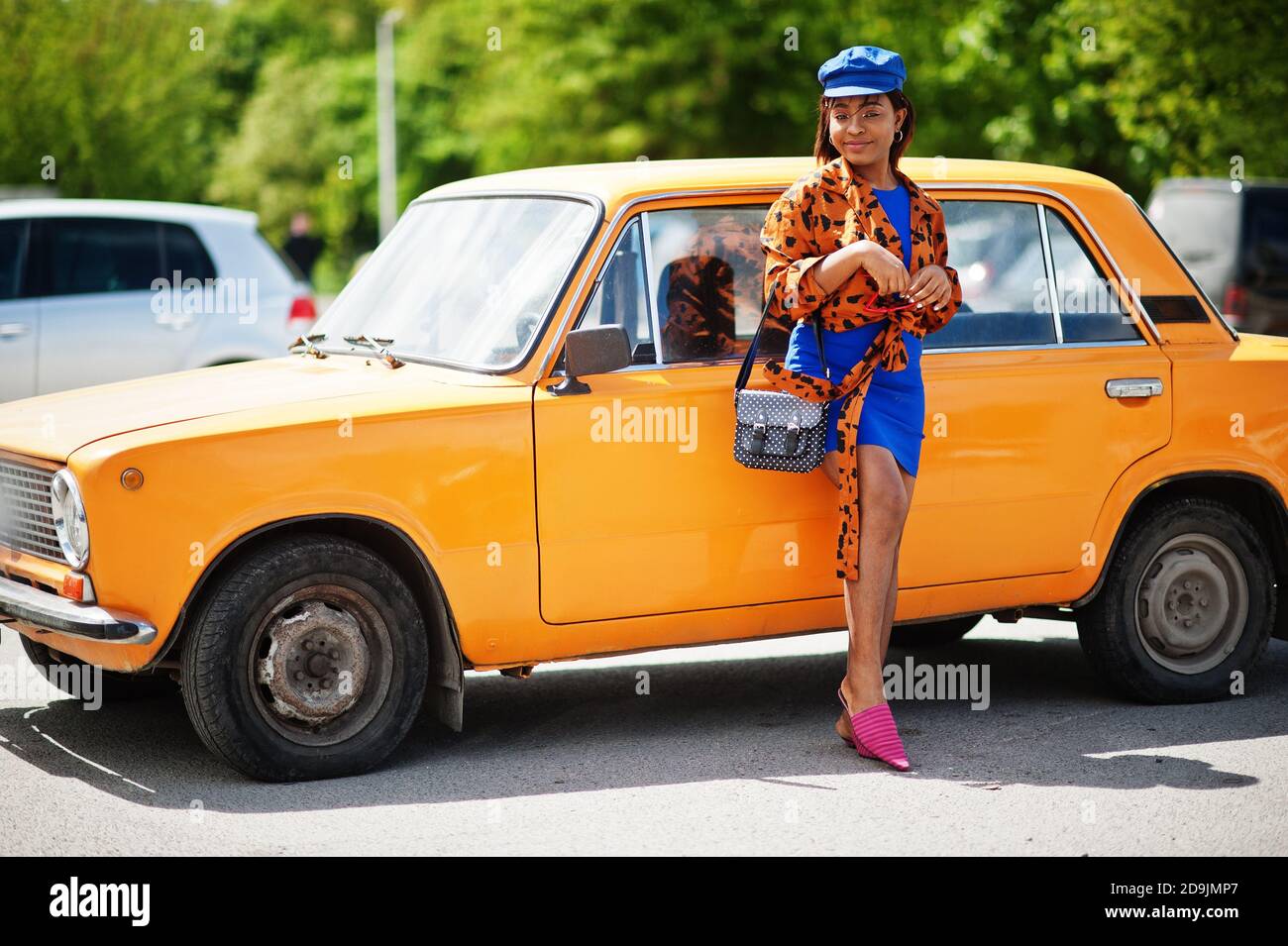 Beautiful african american lady standing near orange classic retro car ...