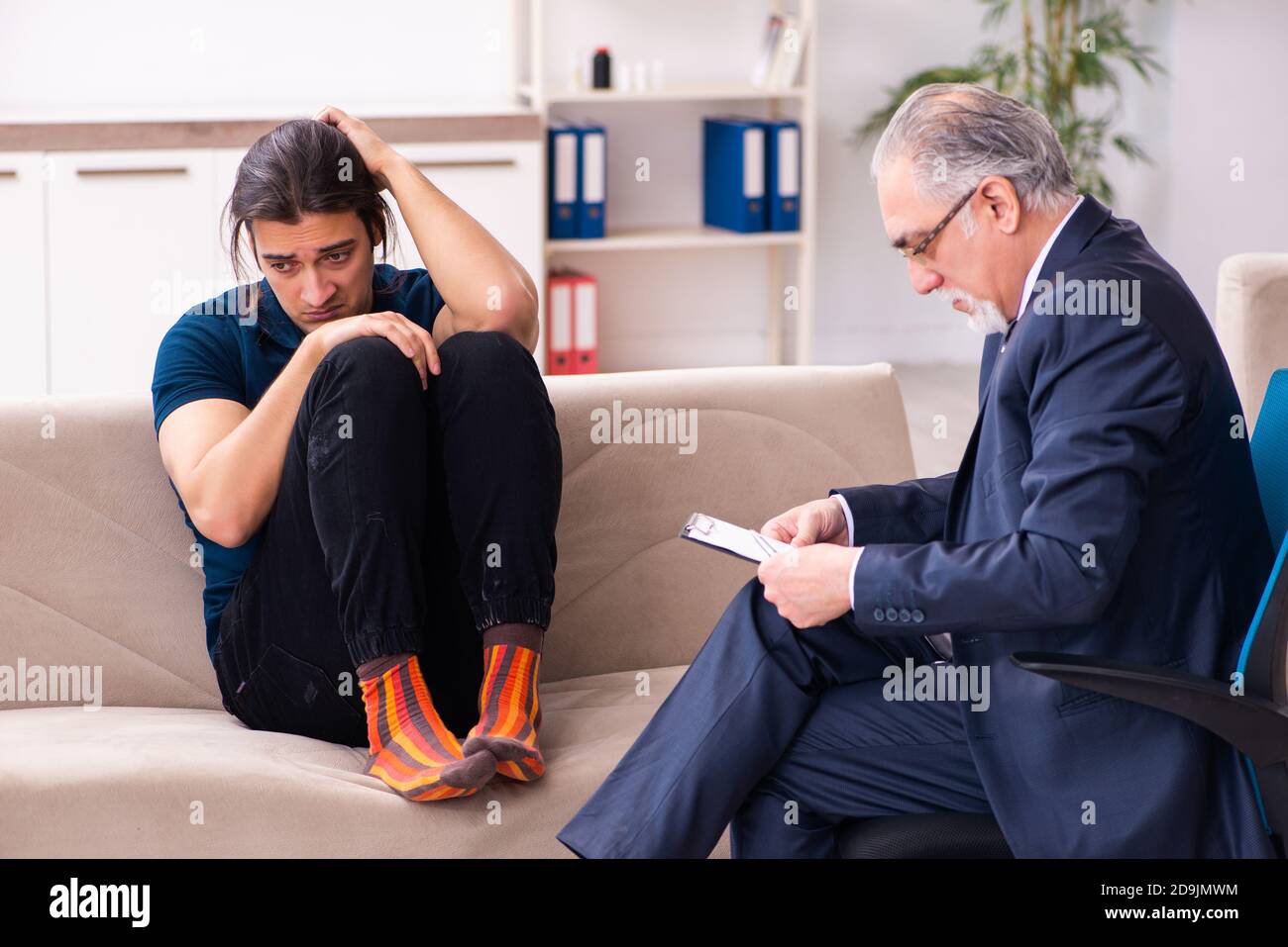 Young man visiting old psychologist Stock Photo - Alamy