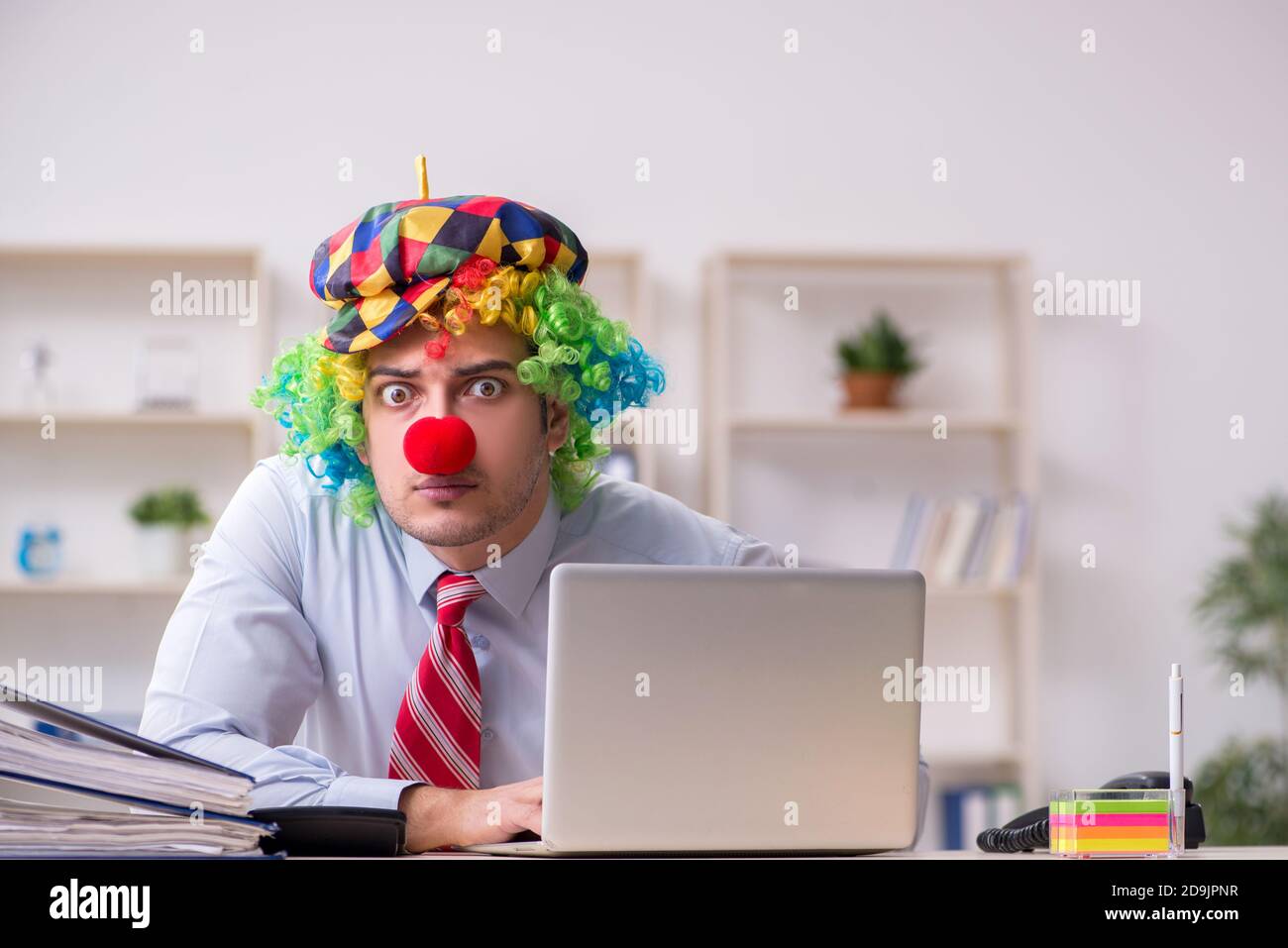 Funny employee clown working in the office room Stock Photo - Alamy