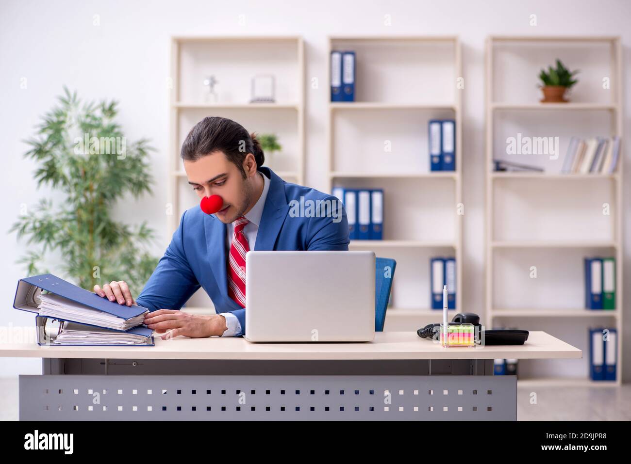 Funny employee clown working in the office room Stock Photo - Alamy
