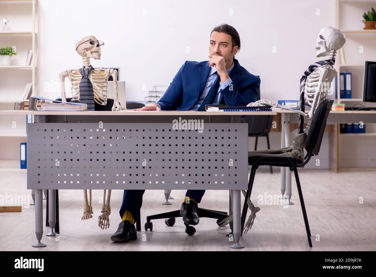 Young employee with skeletons in the office Stock Photo - Alamy