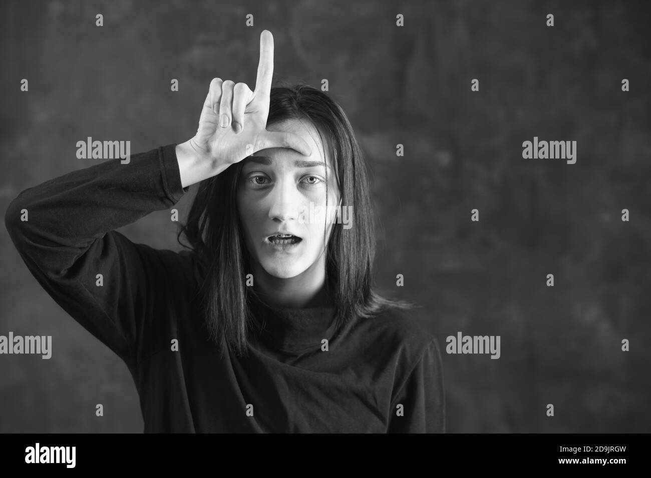 Cute girl shows loser sign. Failure and fiasco concept. Black and white ...