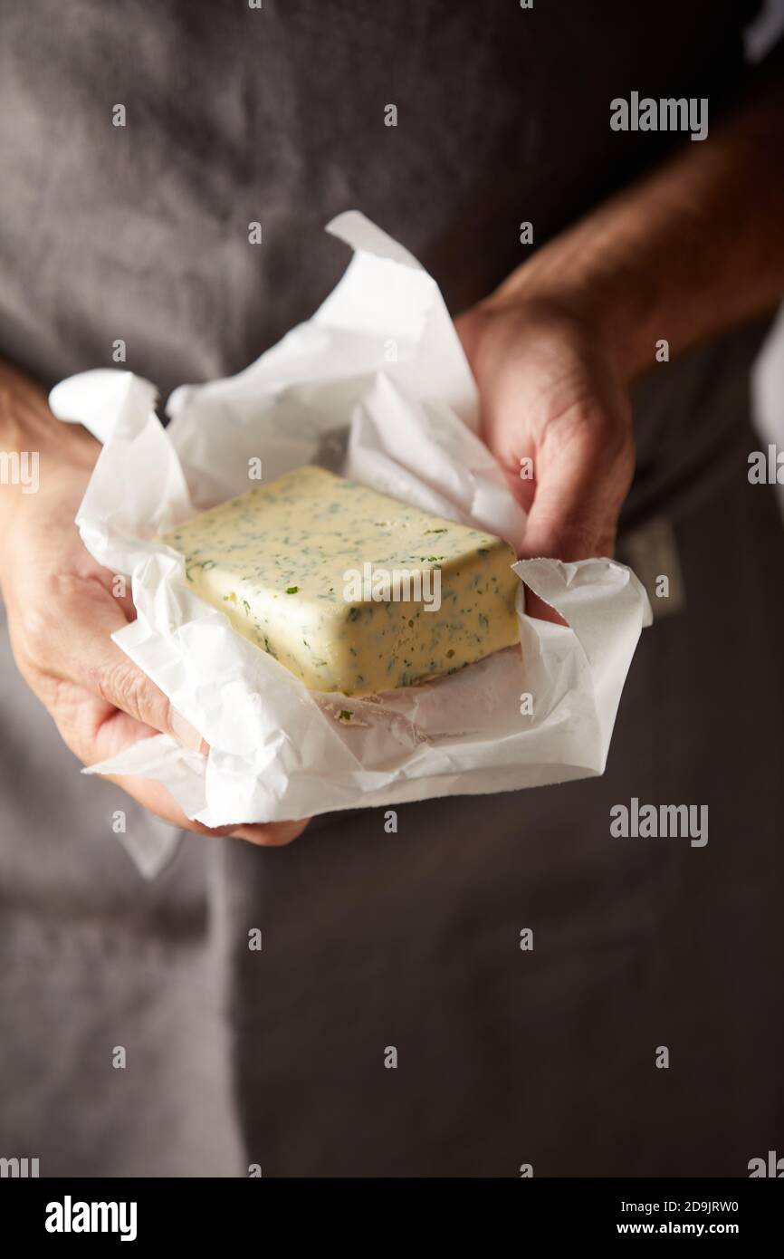 Hands of a chef holding a pat of farm fresh butter seasoned with herbs ...