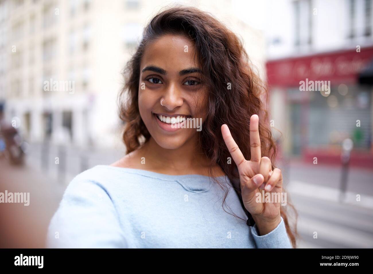 Portrait young Indian woman smiling and taking selfie with peace hand sign Stock Photo - Alamy