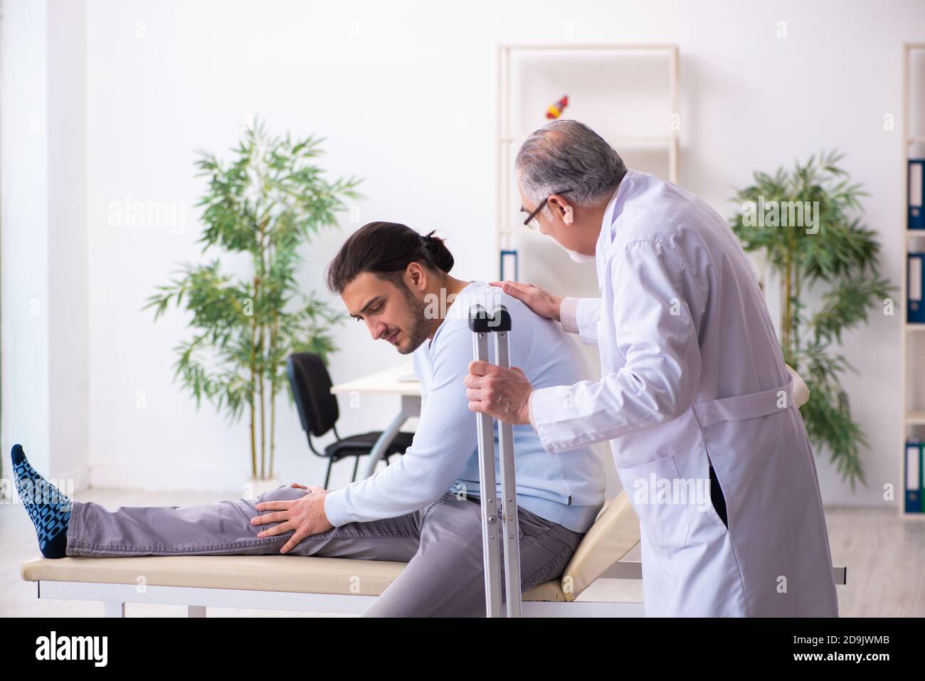Leg injured man visiting old doctor osteopath Stock Photo - Alamy