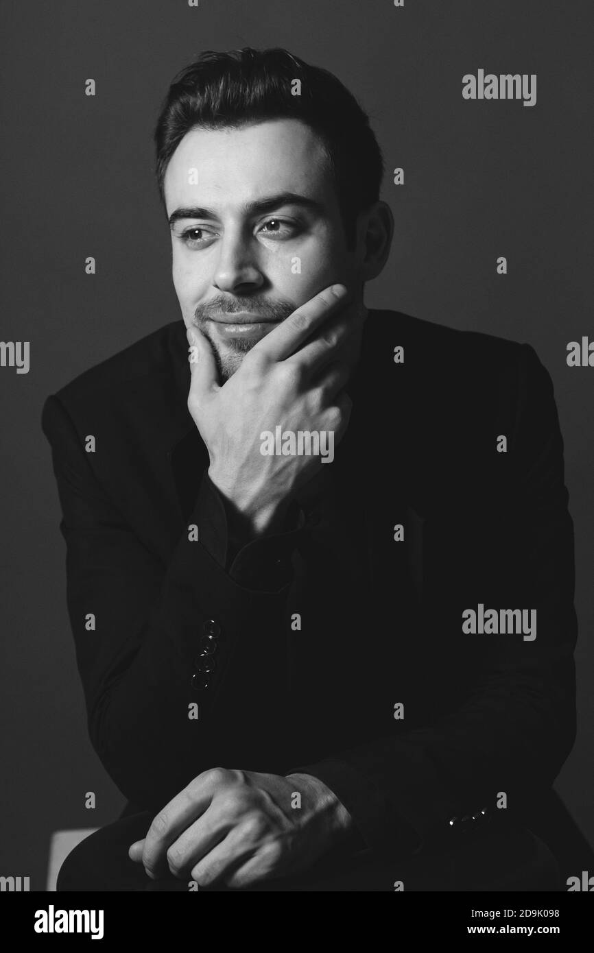 Studio portrait of a young caucasian man in a black jacket, looking to ...