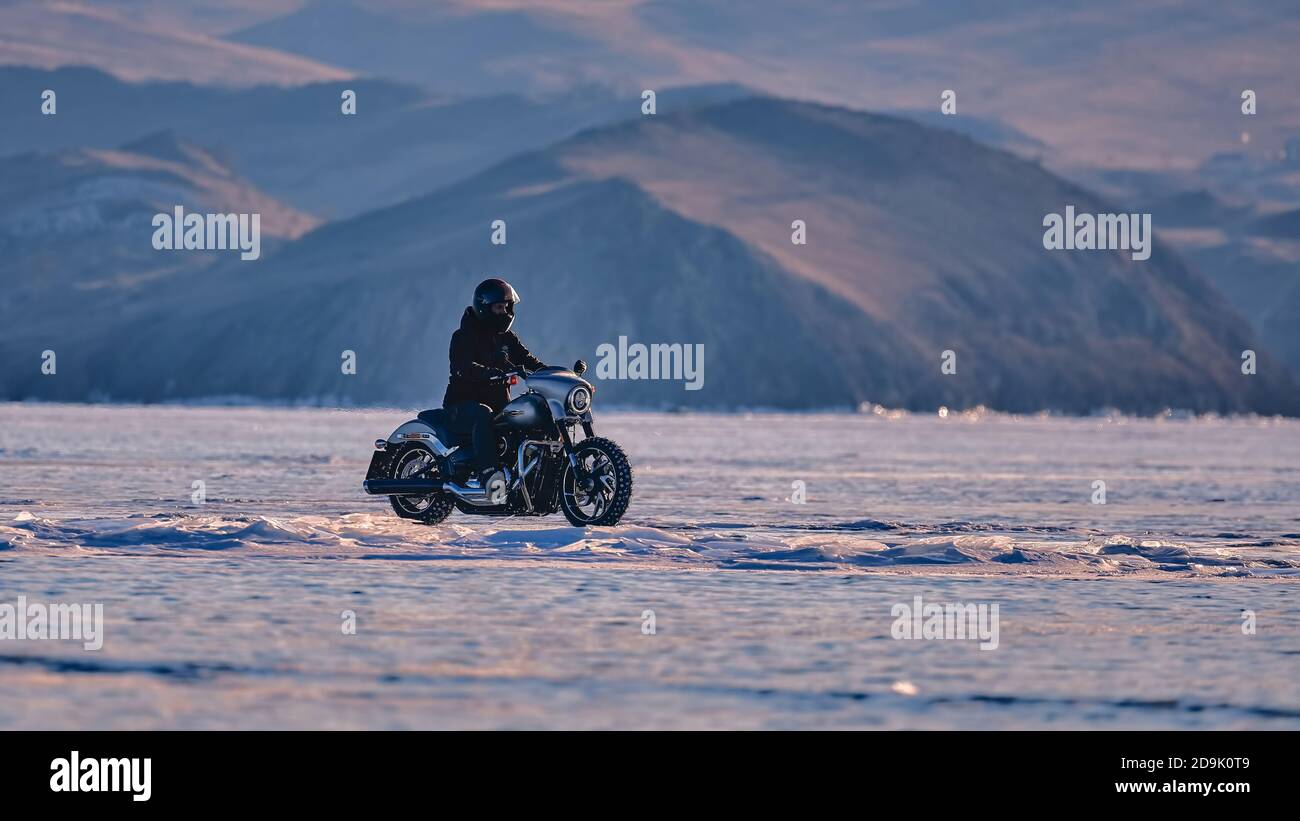 Biker riding on motorcycle Harley Davidson on a frozen lake. 03.08.2019 ...