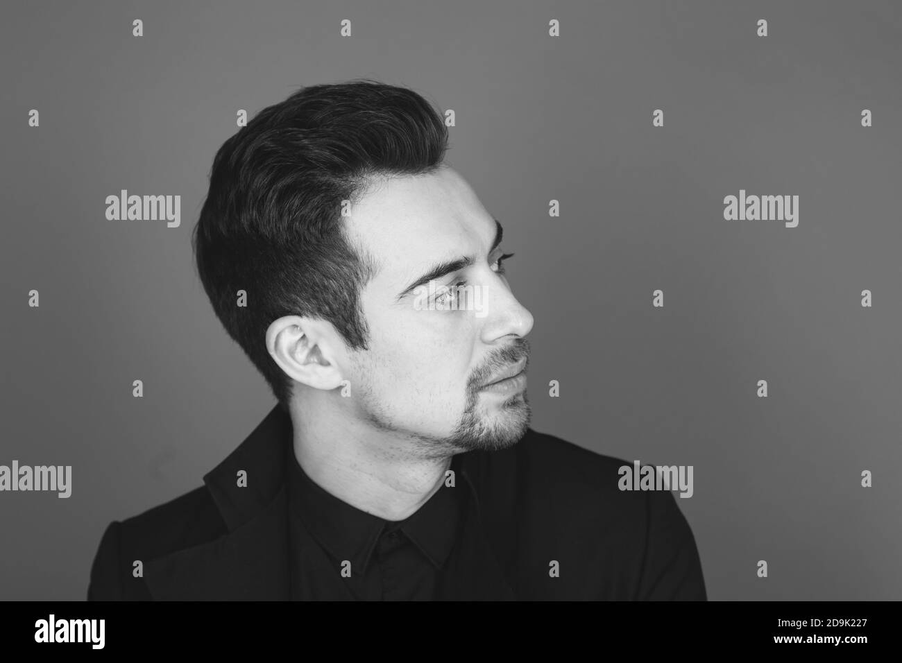 Studio portrait of a young caucasian man in a black jacket, looking to ...