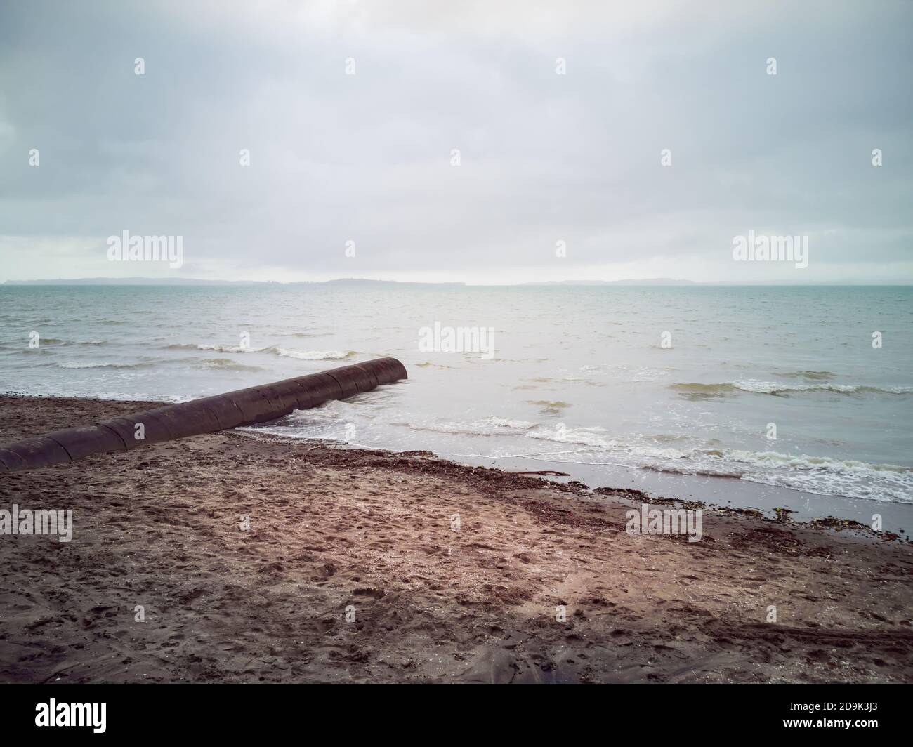 Grey scenery of a sandy beach with a sewage pipe Stock Photo - Alamy