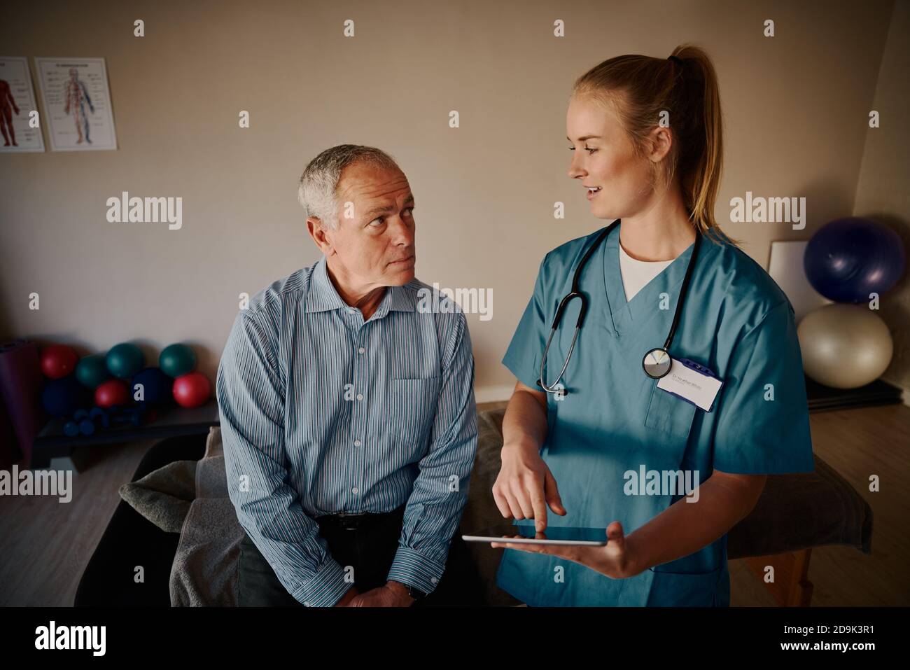 Smiling young doctor holding digital tablet explaining treatment ...
