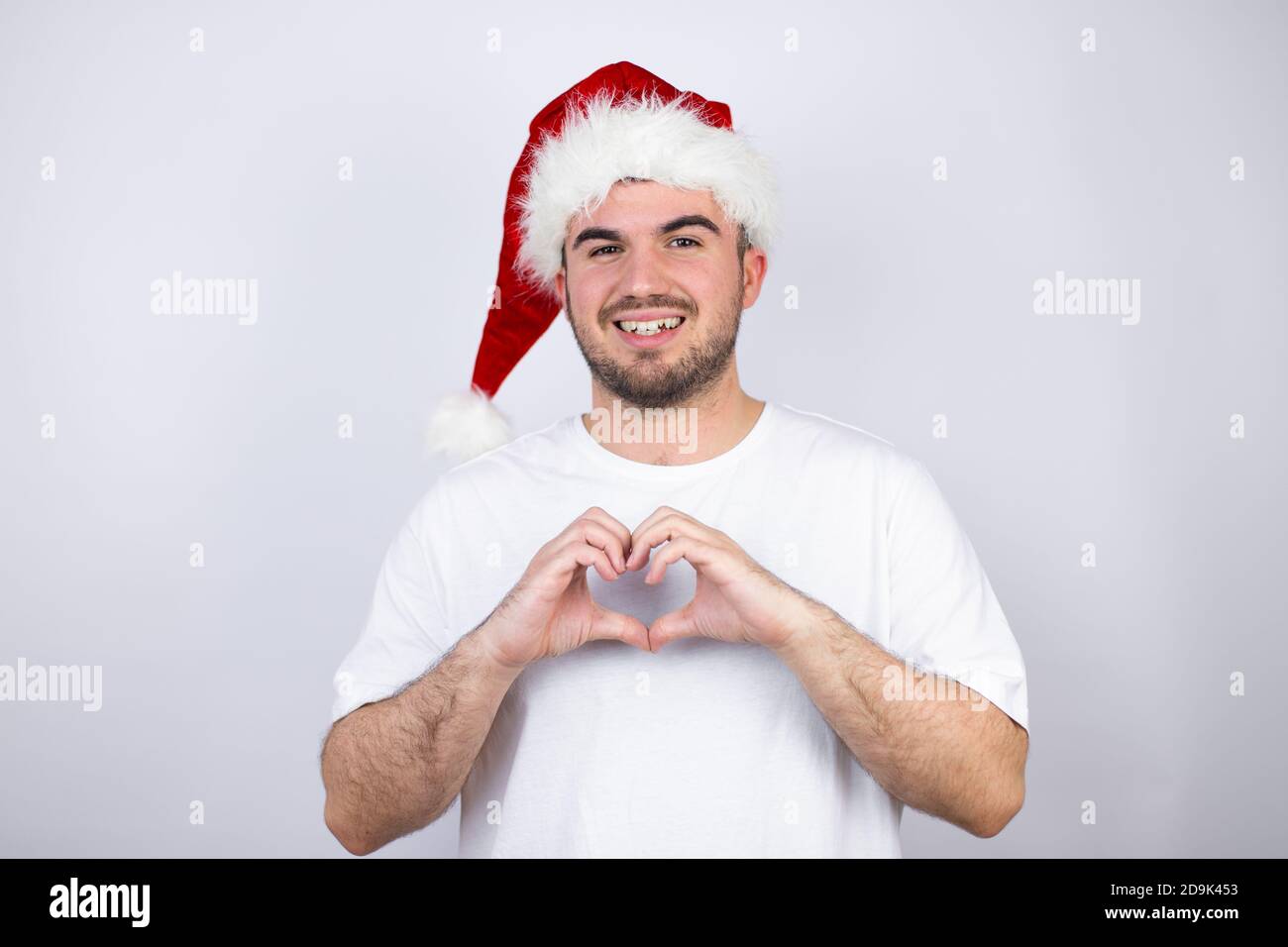 Young handsome man wearing a Santa hat over white background smiling in ...