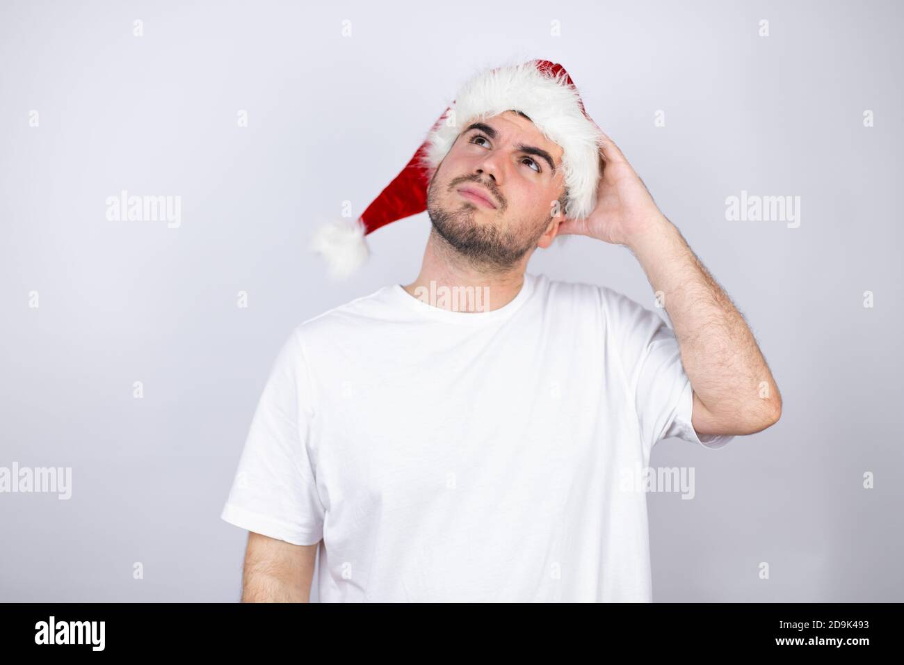 Young handsome man wearing a Santa hat over white background putting ...