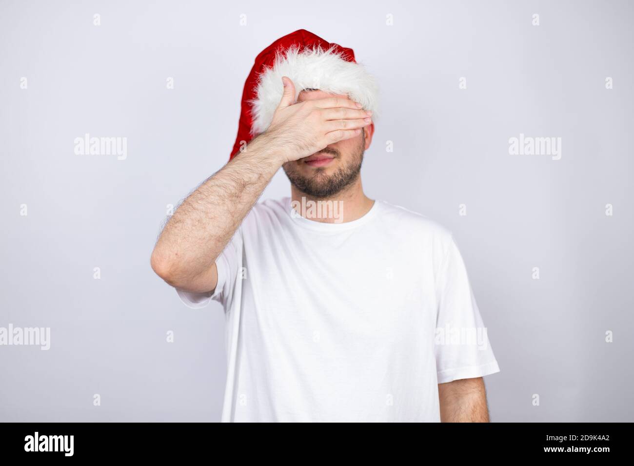Young handsome man wearing a Santa hat over white background serious ...