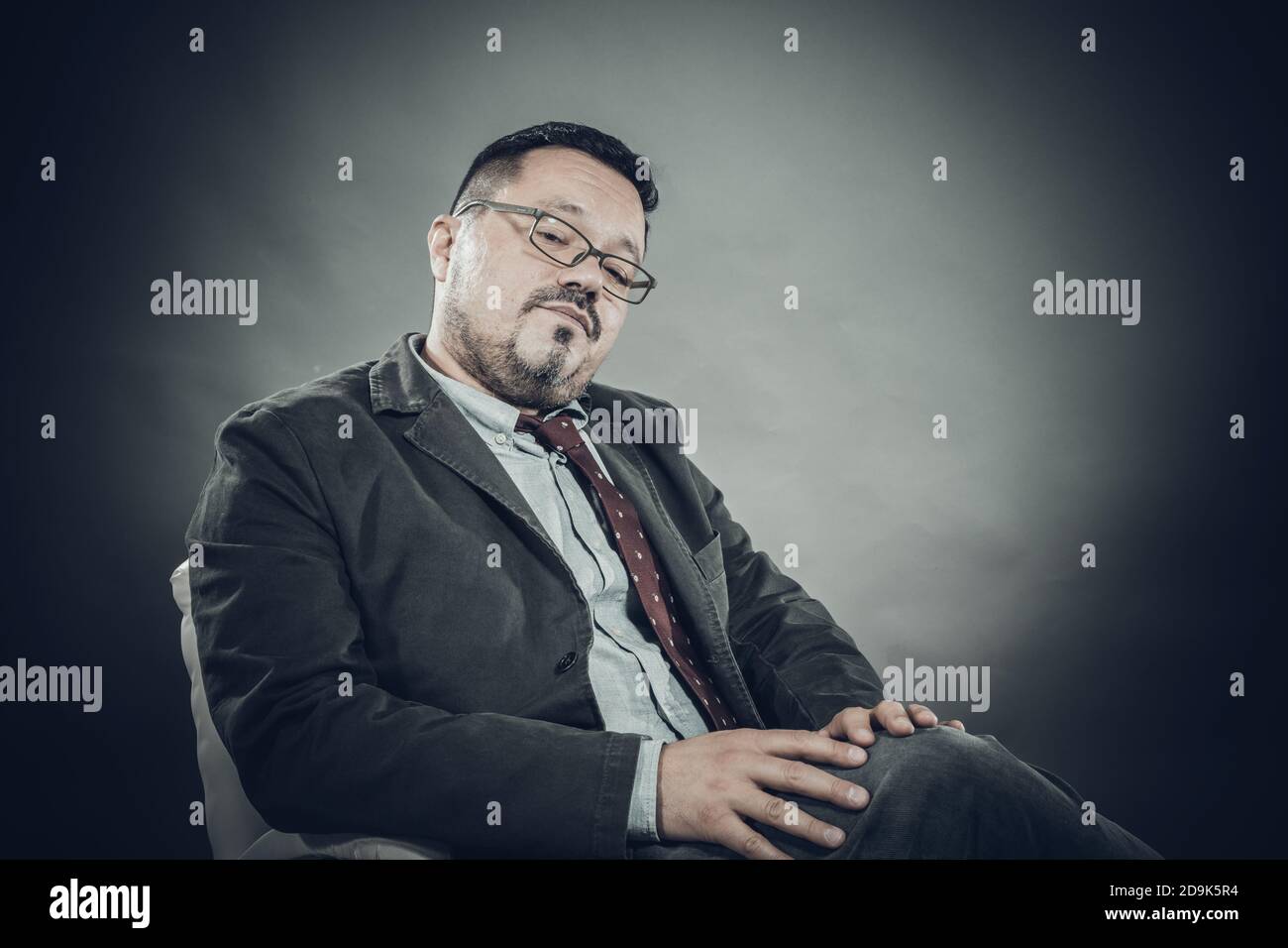 Solid cheerful man in spectacles sitting in chair emotional studio ...