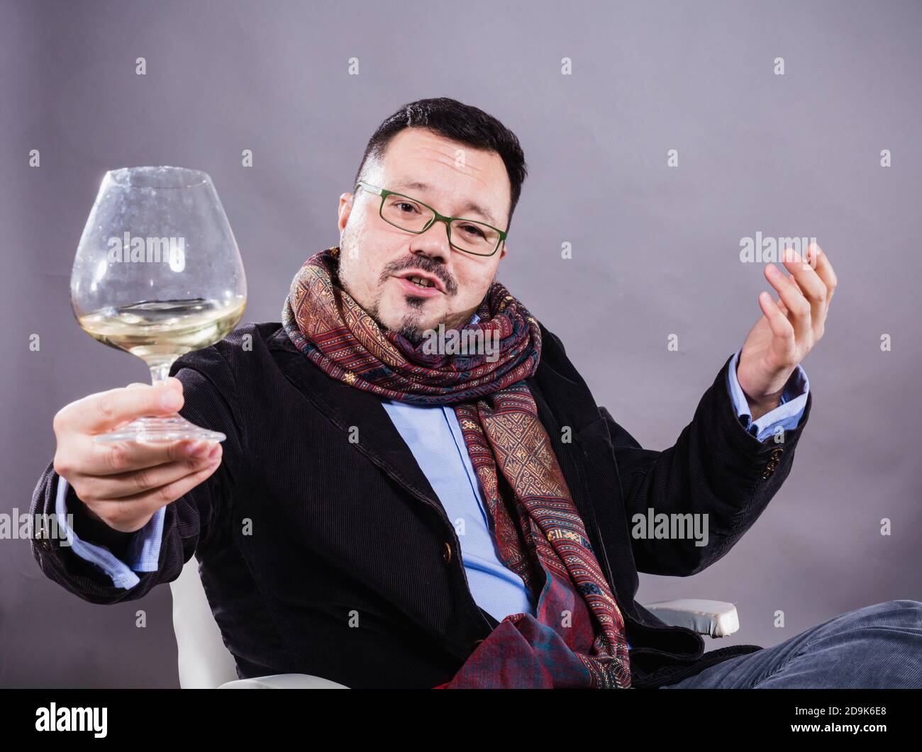 Solid cheerful man in kerchief sitting with glass of wine emotional ...