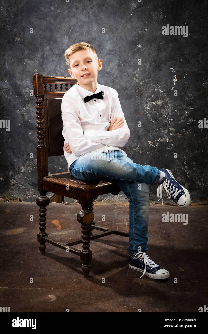 Young cheerful boy sitting on chair studio portrait Stock Photo - Alamy