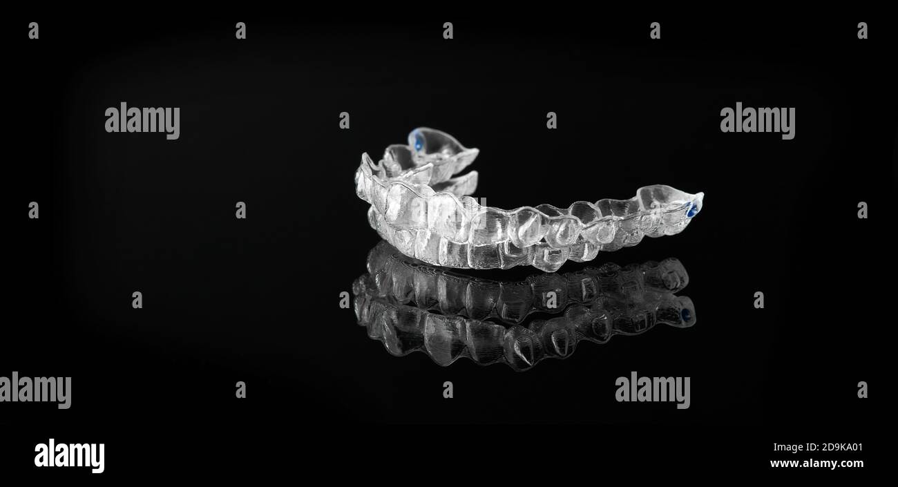 Invisible orthodontics cosmetic brackets on black background, tooth ...