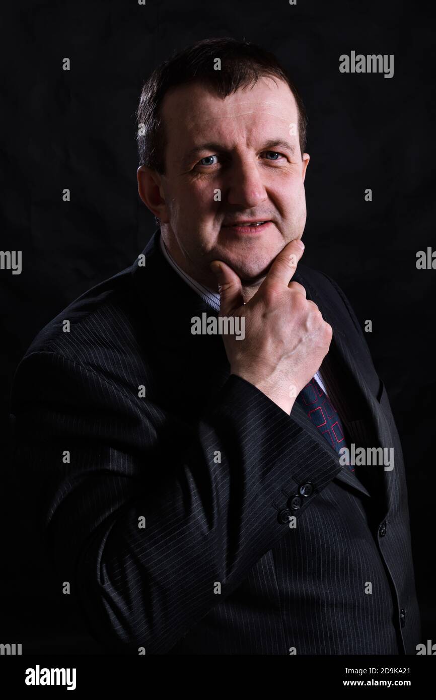 Middle aged solid man dressed in suit studio portrait on black ...