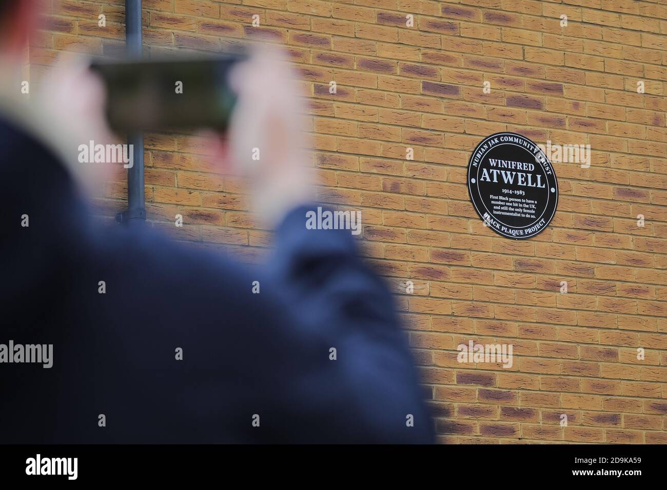 A man photographs a black plaque dedicated to Winifred Atwell in ...