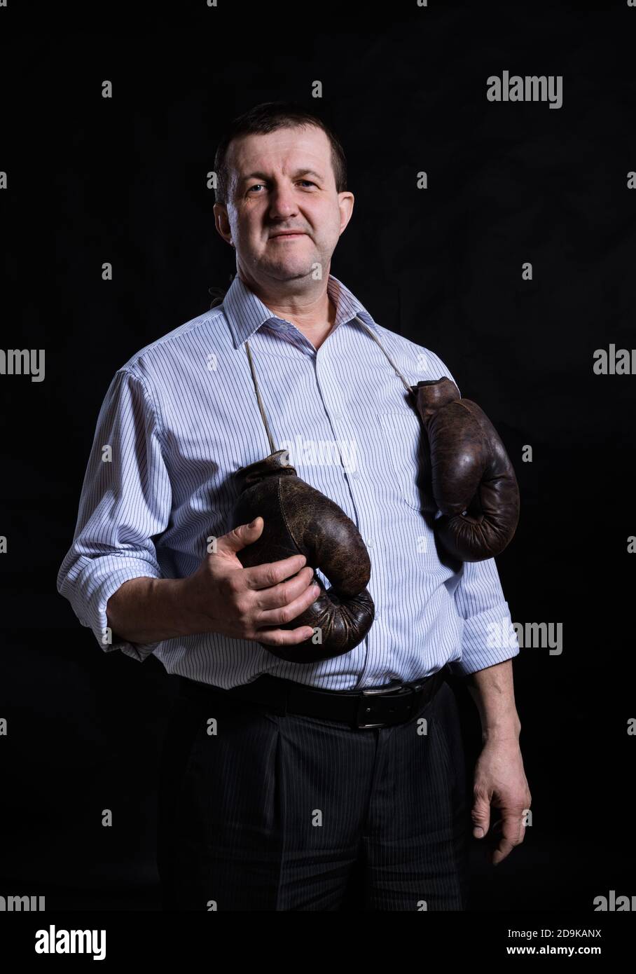 Middle aged solid man with old boxing gloves dressed in shirt studio ...
