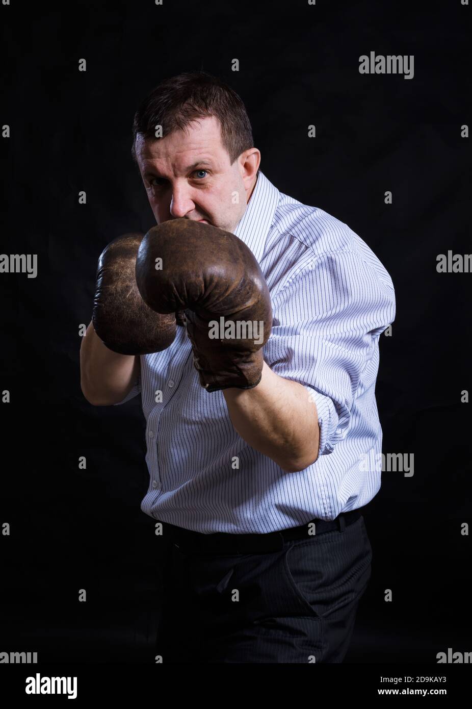 Middle aged solid man with old boxing gloves dressed in shirt studio ...