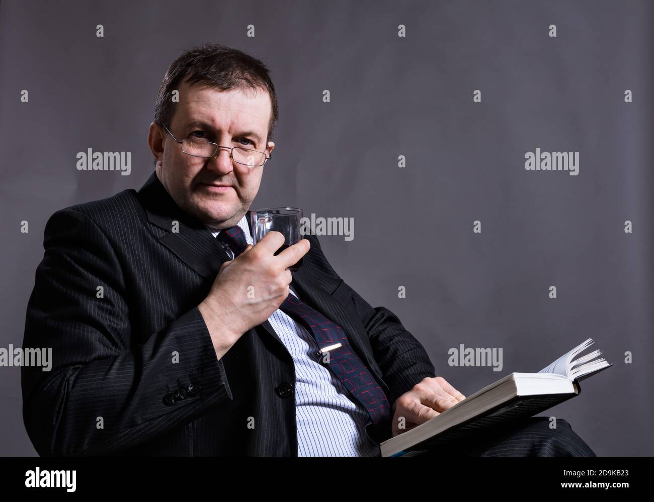 Middle aged solid professor with book studio portrait Stock Photo - Alamy