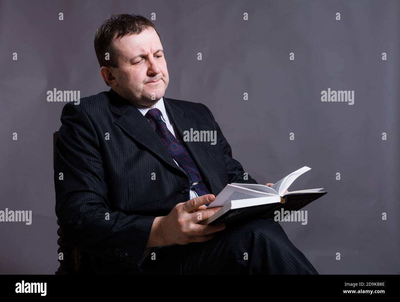 Middle aged solid professor with book studio portrait Stock Photo - Alamy