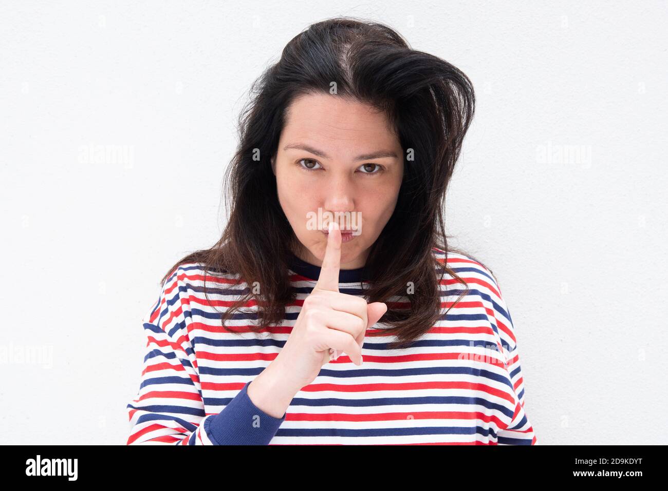 Close up portrait young woman with finger over lips against isolated ...