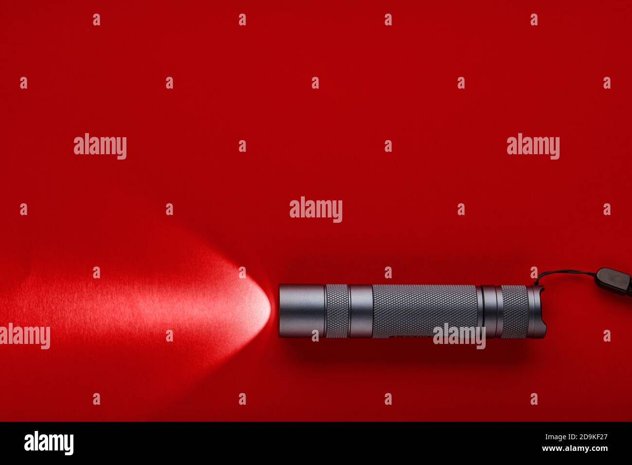Flashlight on a red background. A beam of light from a flashlight ...