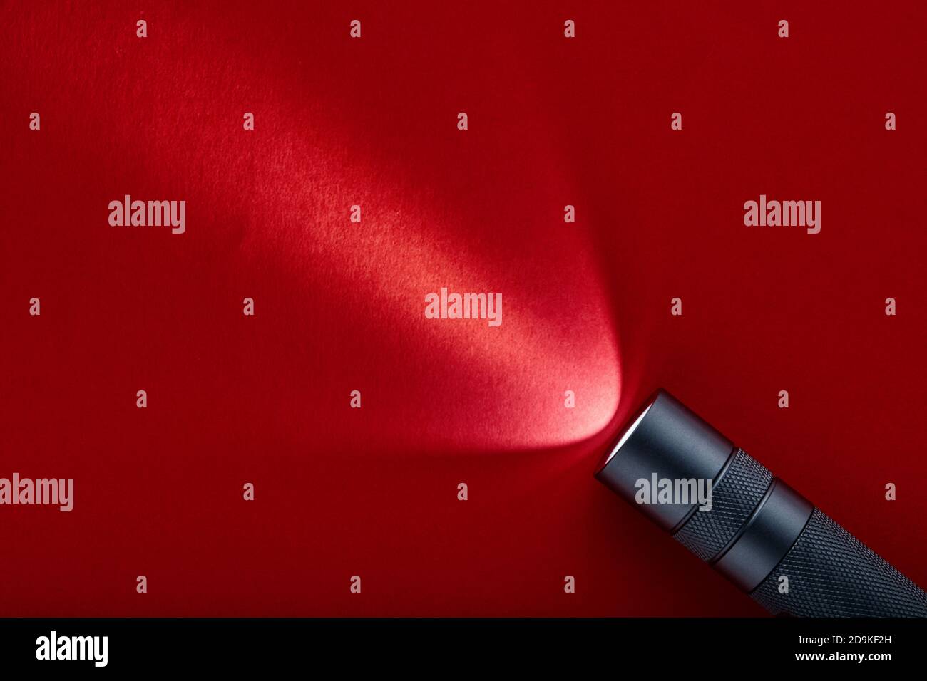 Flashlight on a red background. A beam of light from a flashlight ...