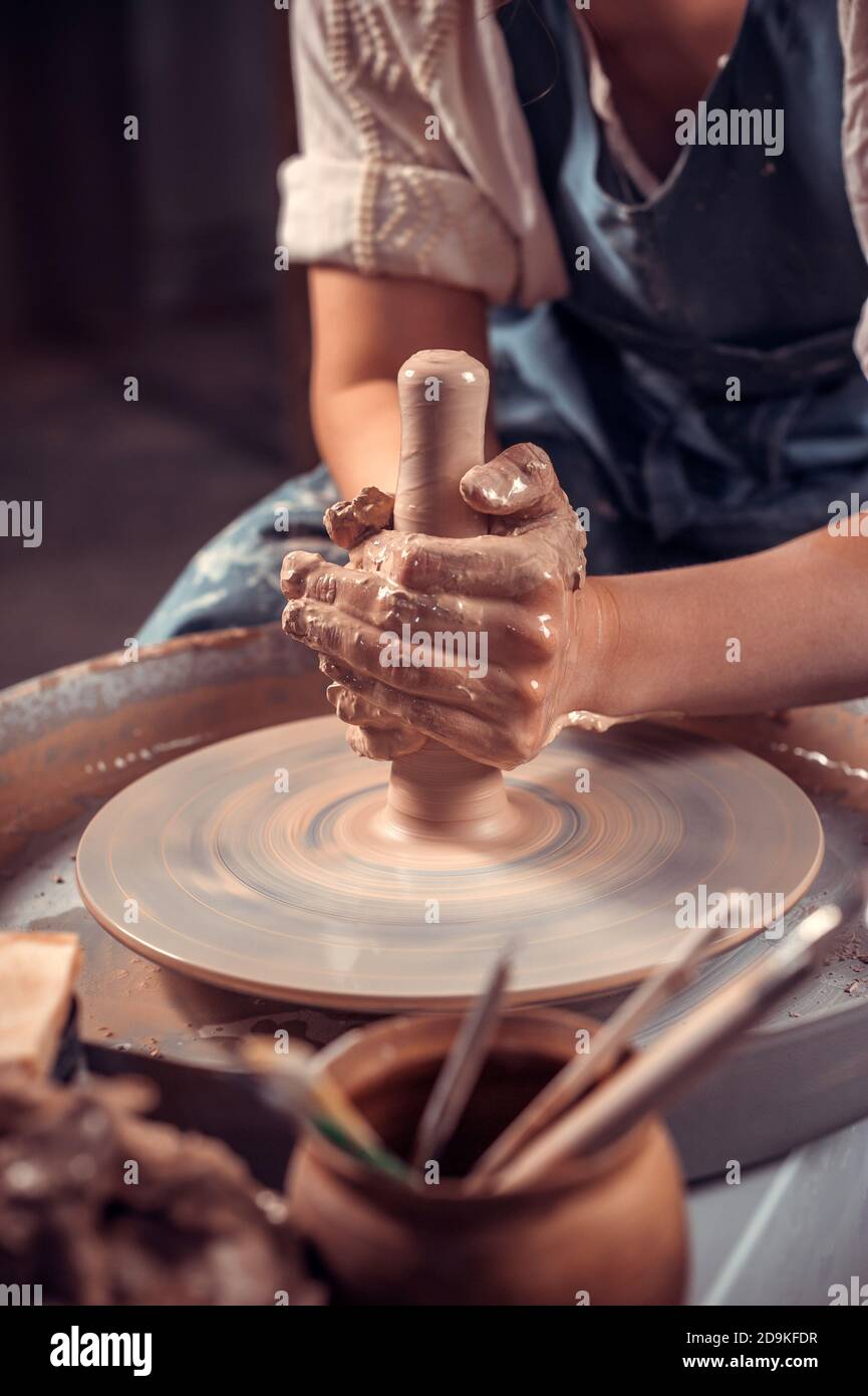 Hands of the master potter and vase of clay on the potter's wheel close ...