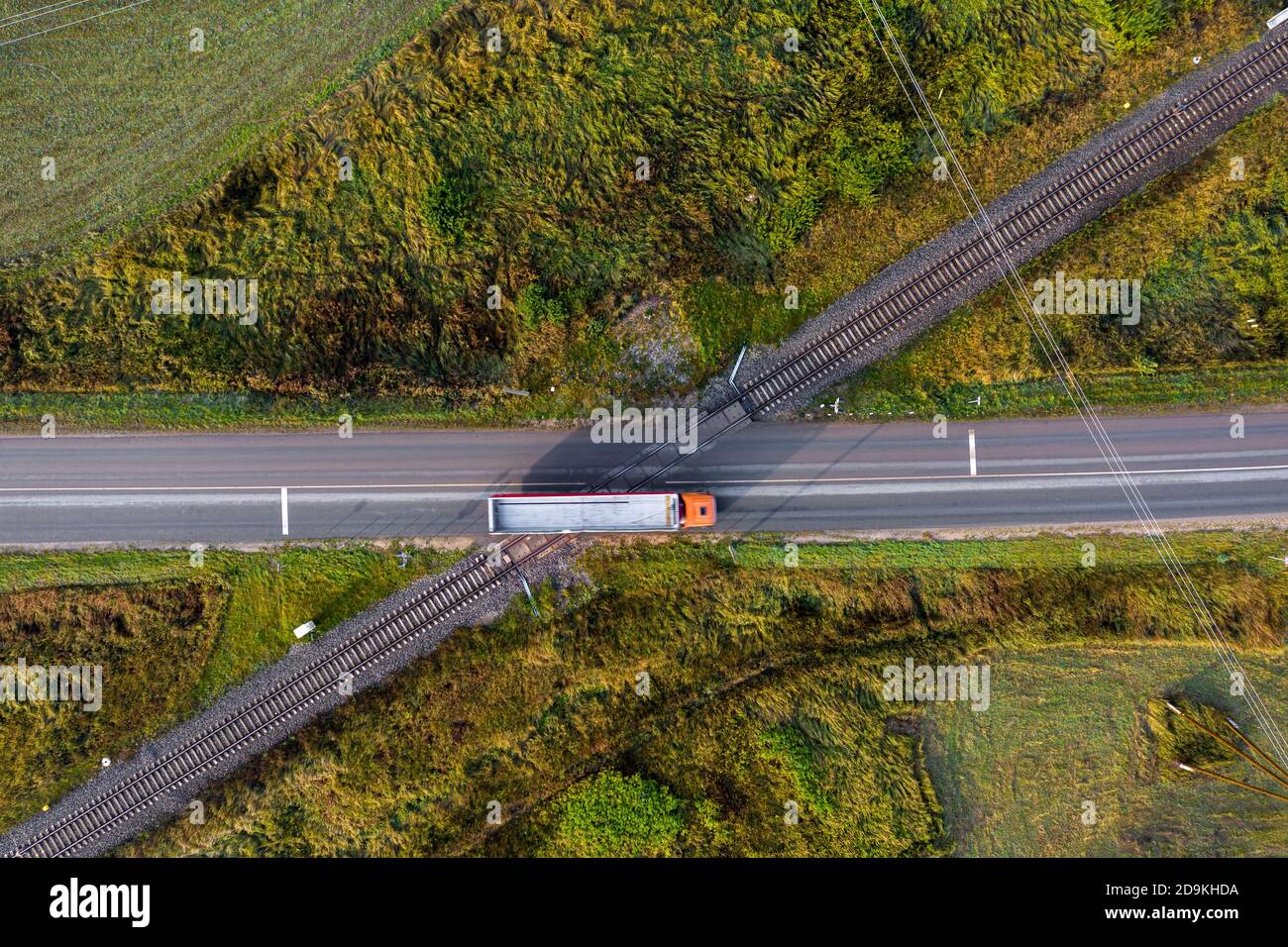 aerial view of railroad tracks crossing a asphalt road with cars in ...