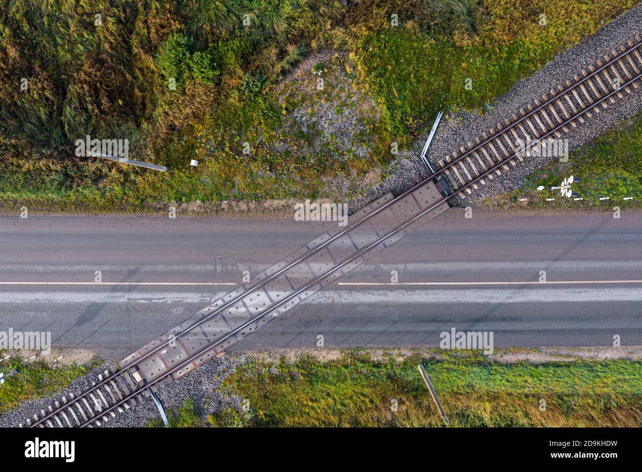 aerial view of railroad tracks crossing a asphalt road in rural area ...