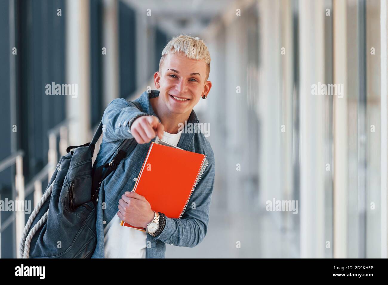 Male young student in jeans clothes is in corridor of a college with ...