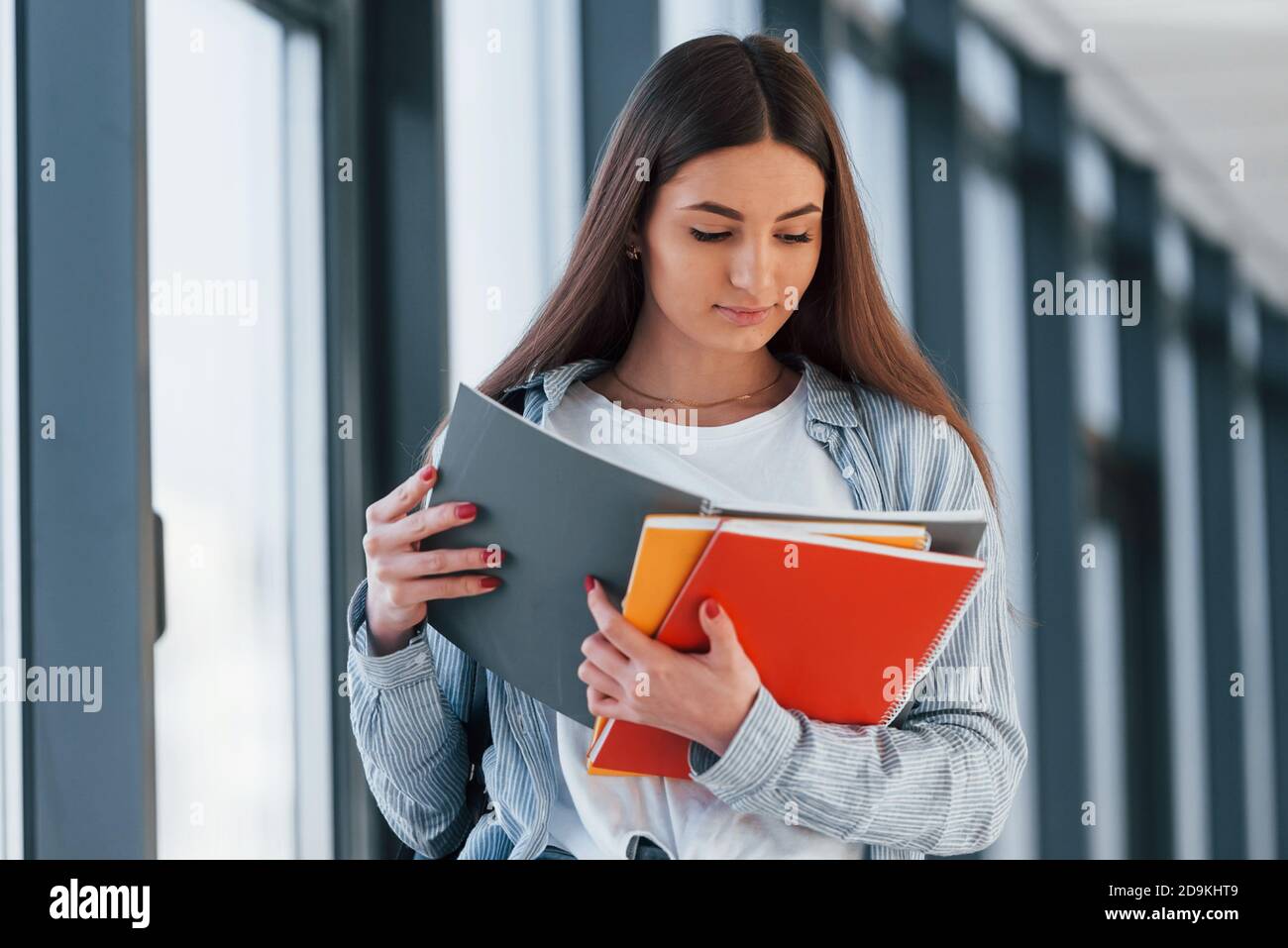 Female young student reading information from notepad in corridor of a ...