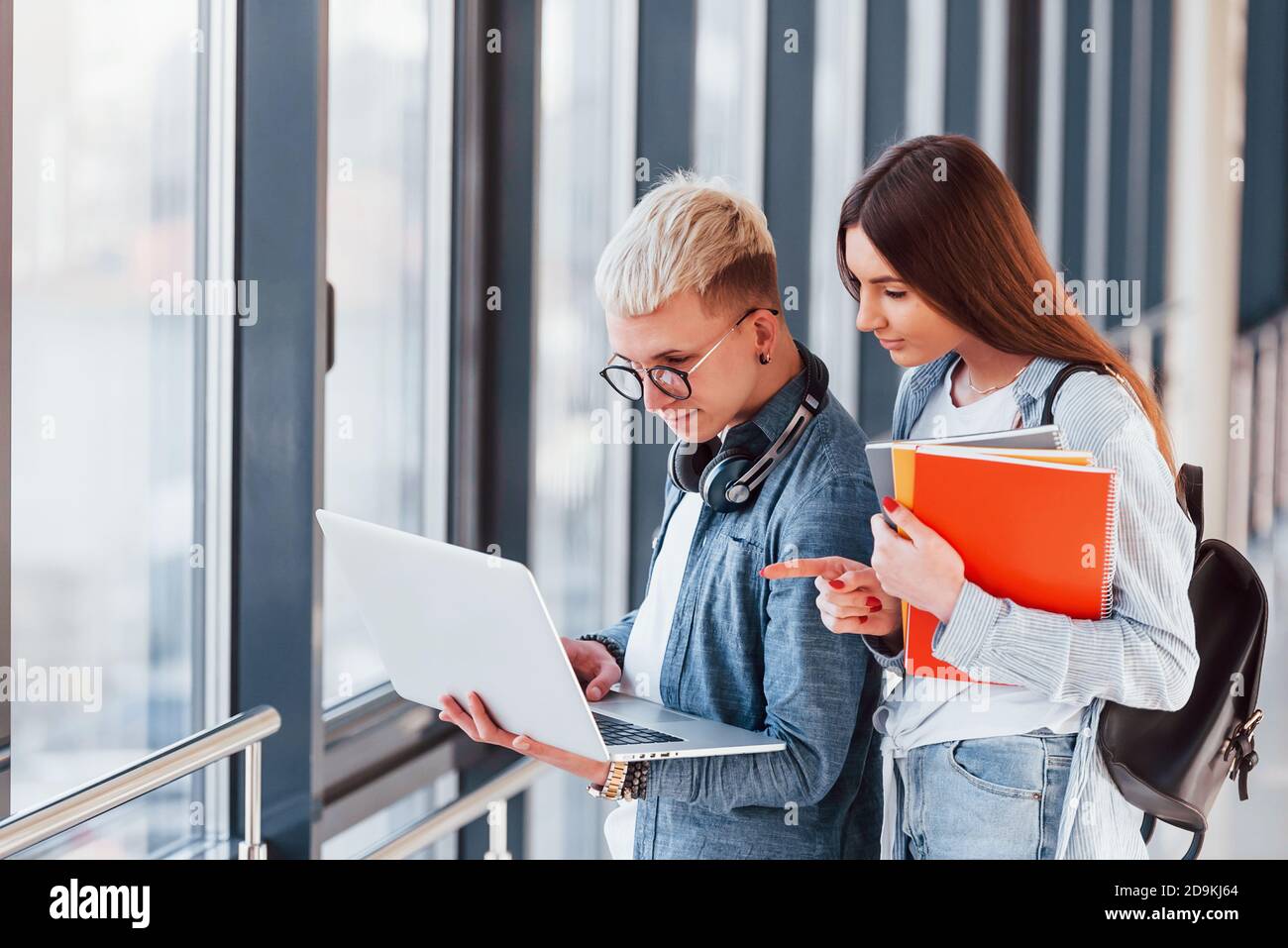 Two young student friends together in a corridor of a college with ...