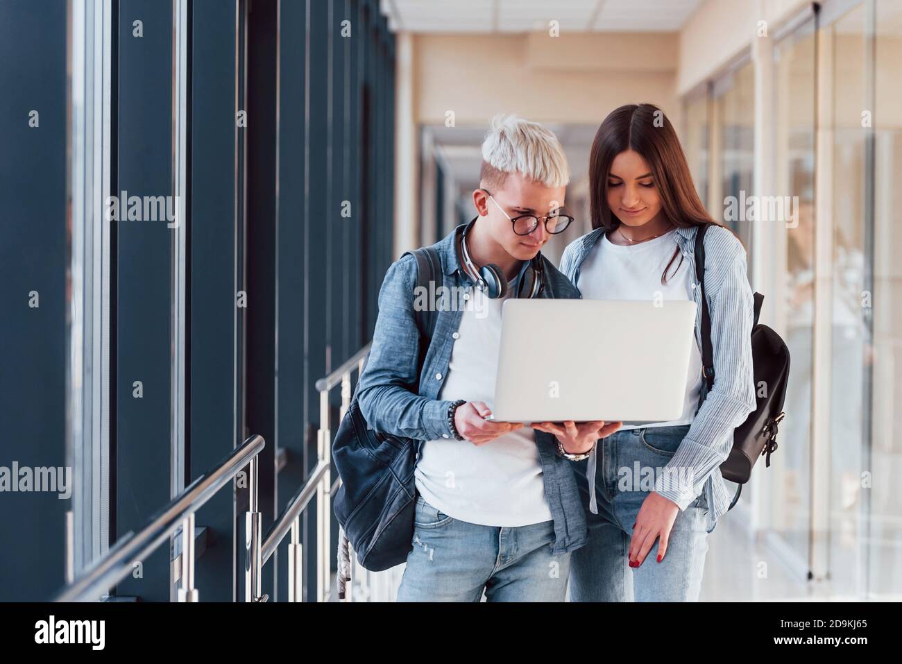 Two young student friends together in a corridor of a college with ...