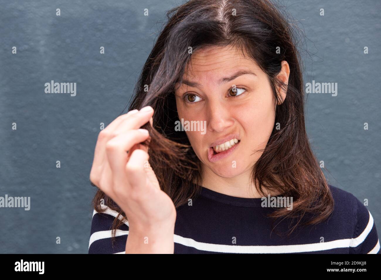 Close up portrait young woman holding hair with unhappy expression ...