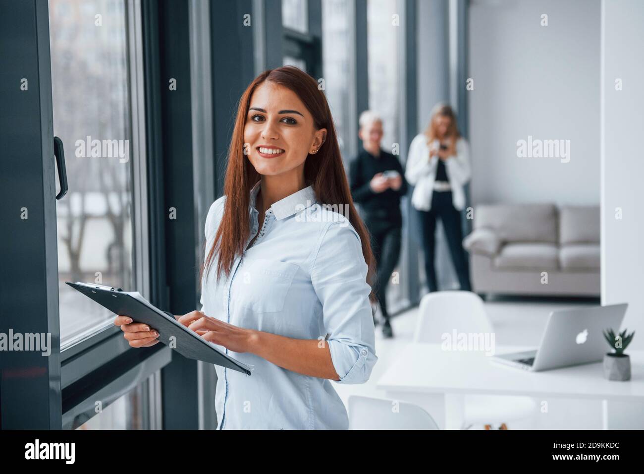 Portrait of woman with notepad that standing in front of group of young ...